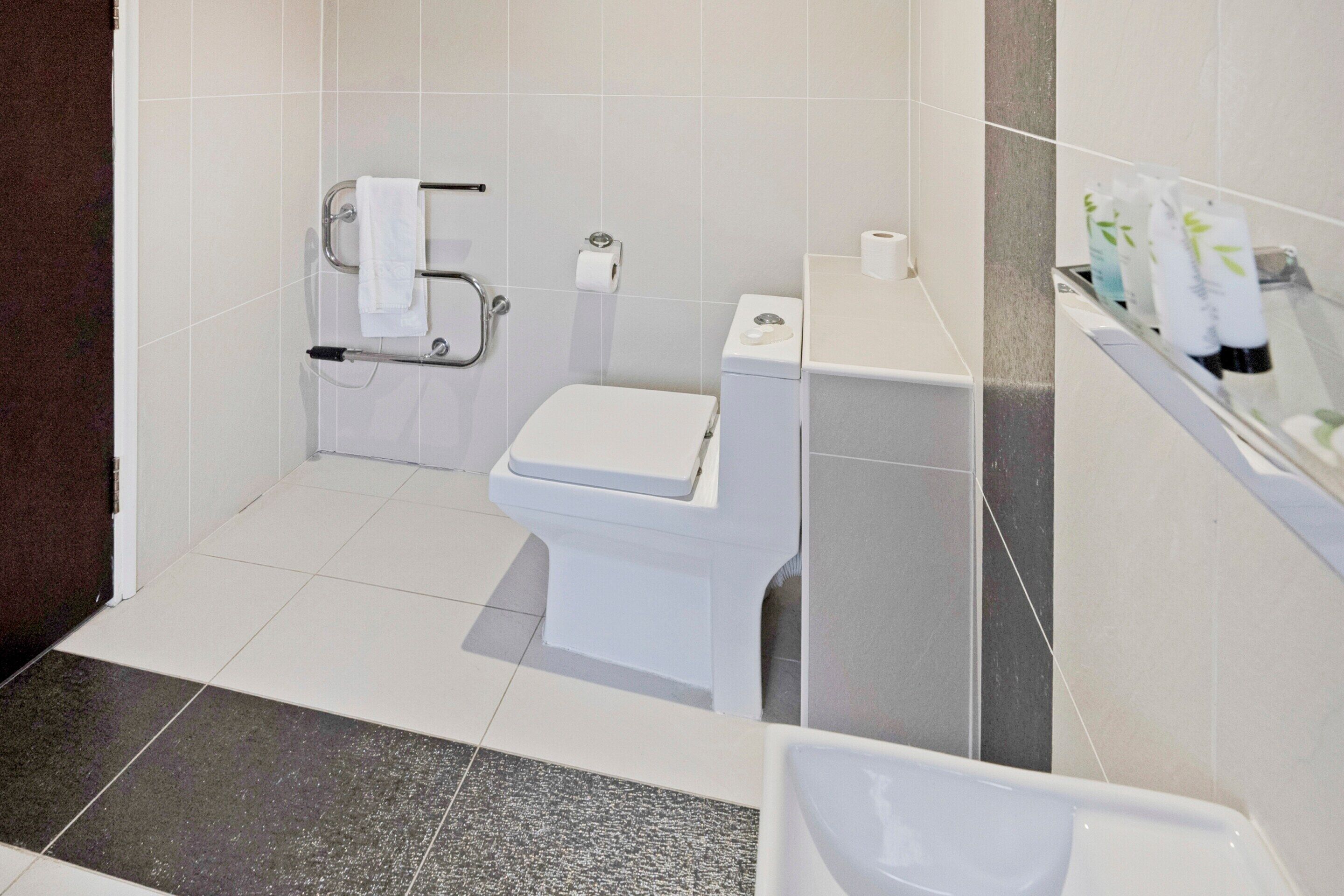 Uma casa de banho moderna com sanita, porta-toalhas e um armário com produtos de higiene pessoal.