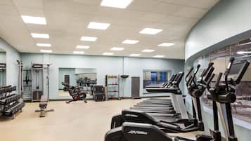 Uma academia com esteiras, halteres e aparelhos de musculação.