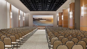 Sala de conferências com fileiras de cadeiras voltadas para uma tela grande exibindo uma vista panorâmica.