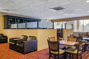 Um saguão de hotel com área de estar, balcão de recepção e uma grande janela que oferece vista para o exterior.