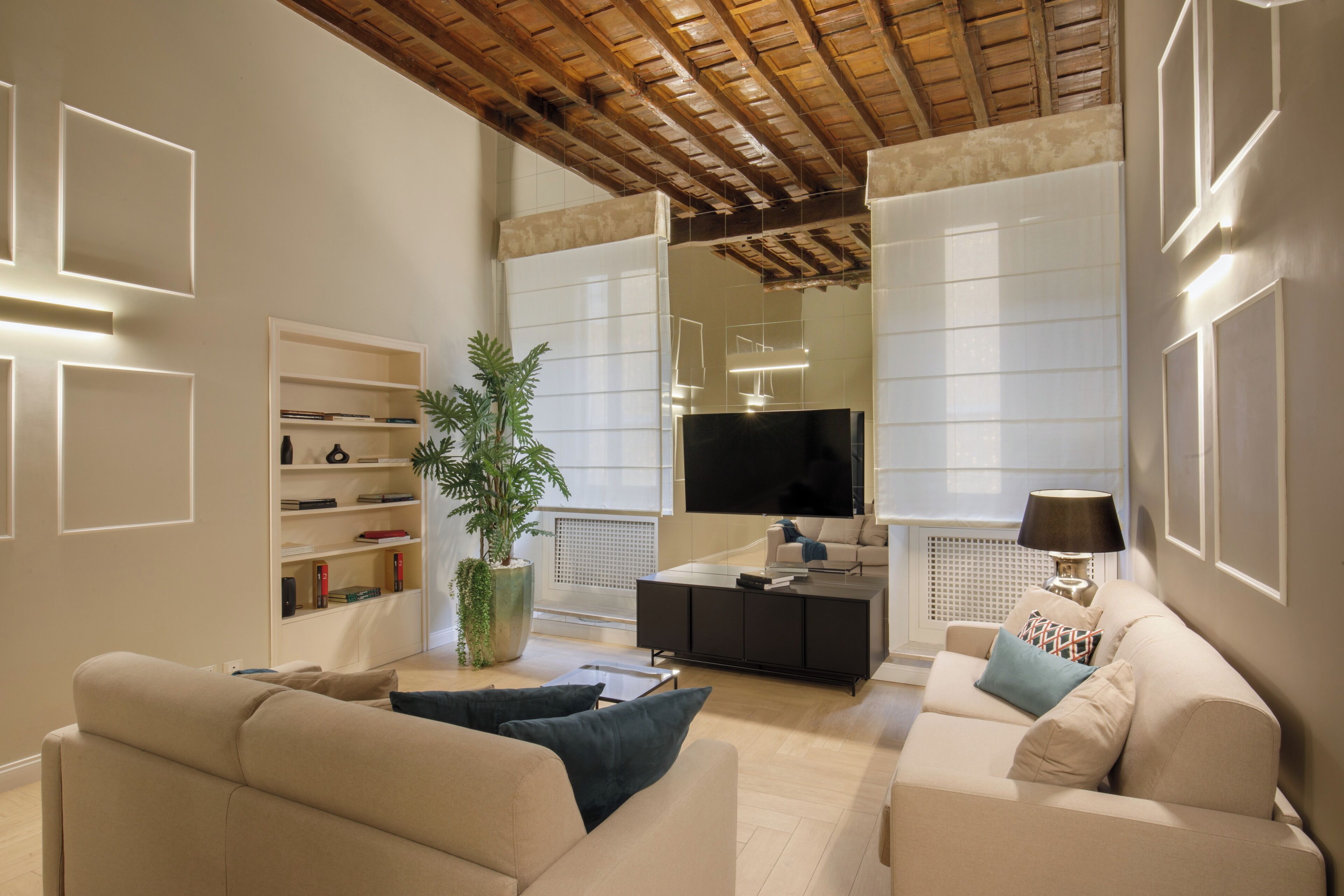 Uma sala de estar moderna com teto de madeira, uma televisão grande e uma planta.