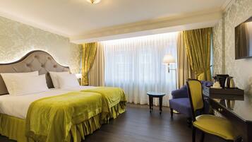 Quarto de hotel com uma cama grande, uma mesa com cadeira e uma televisão na parede.