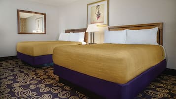 Quarto de hotel com duas camas, um espelho, uma obra de arte emoldurada e um tapete estampado.