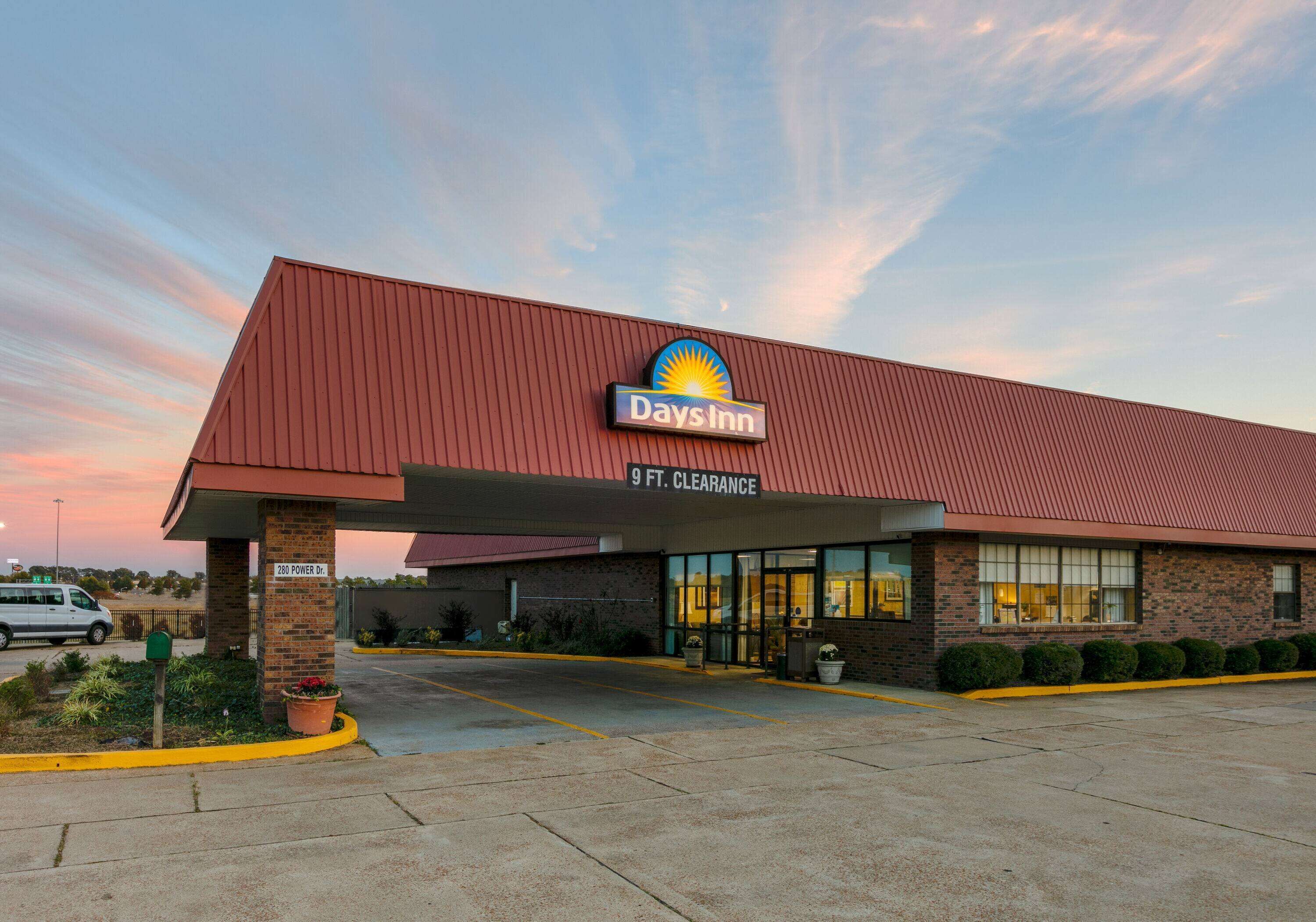 Um hotel Days Inn com placa de 2,7 metros de altura, fachada de tijolos e céu azul ao fundo.