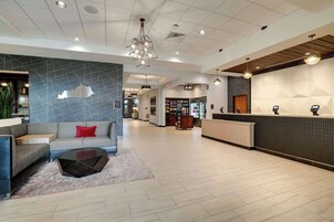 Um lobby de hotel moderno com balcão de atendimento, área de estar e uma loja.