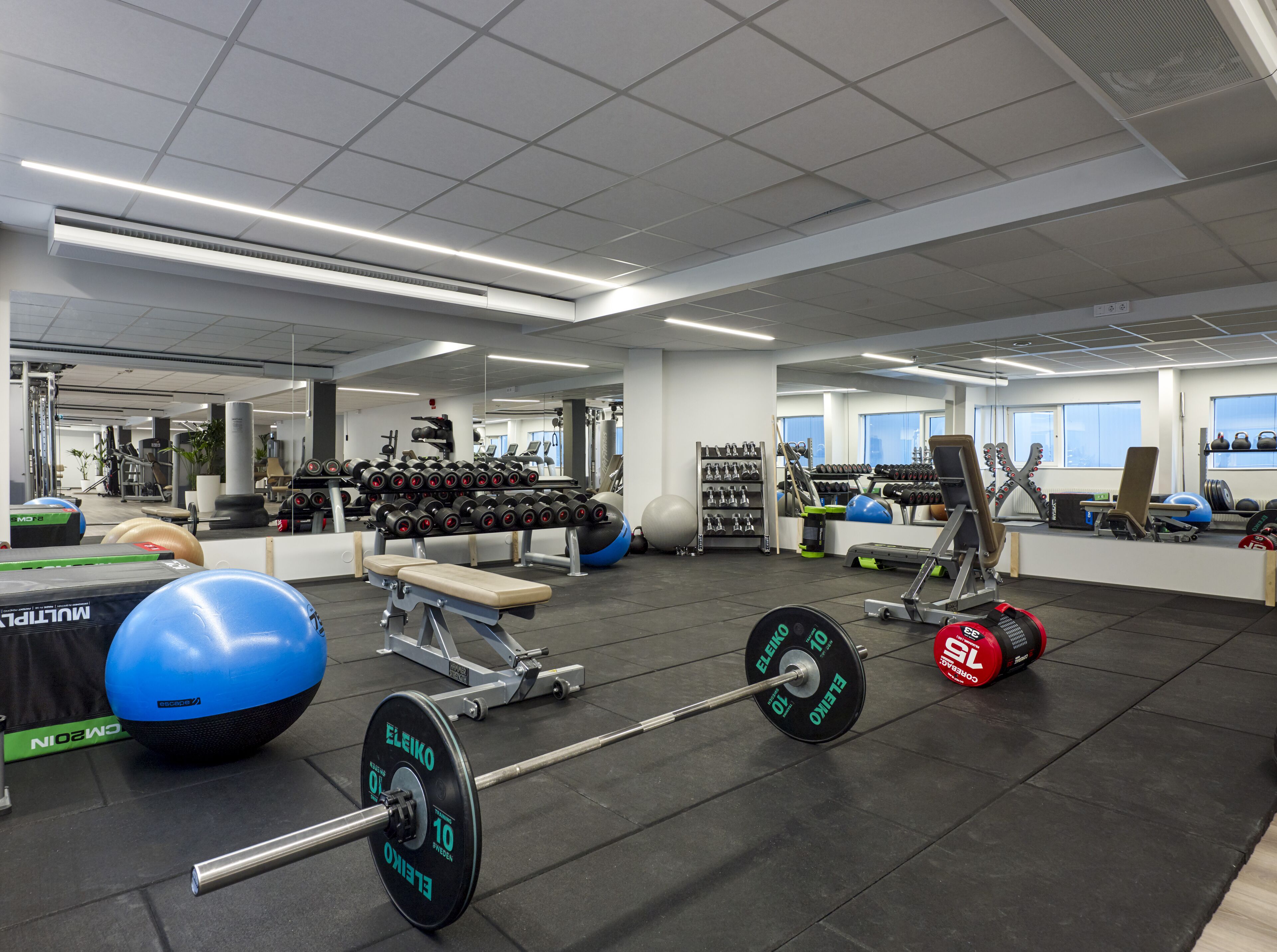 Uma academia com equipamentos de musculação, bolas de exercício e bancos.