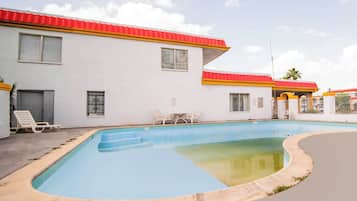 Piscina com um edifício de telhado vermelho ao fundo.