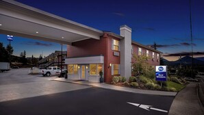 Um hotel Best Western com fachada vermelha, um posto de gasolina e um estacionamento.