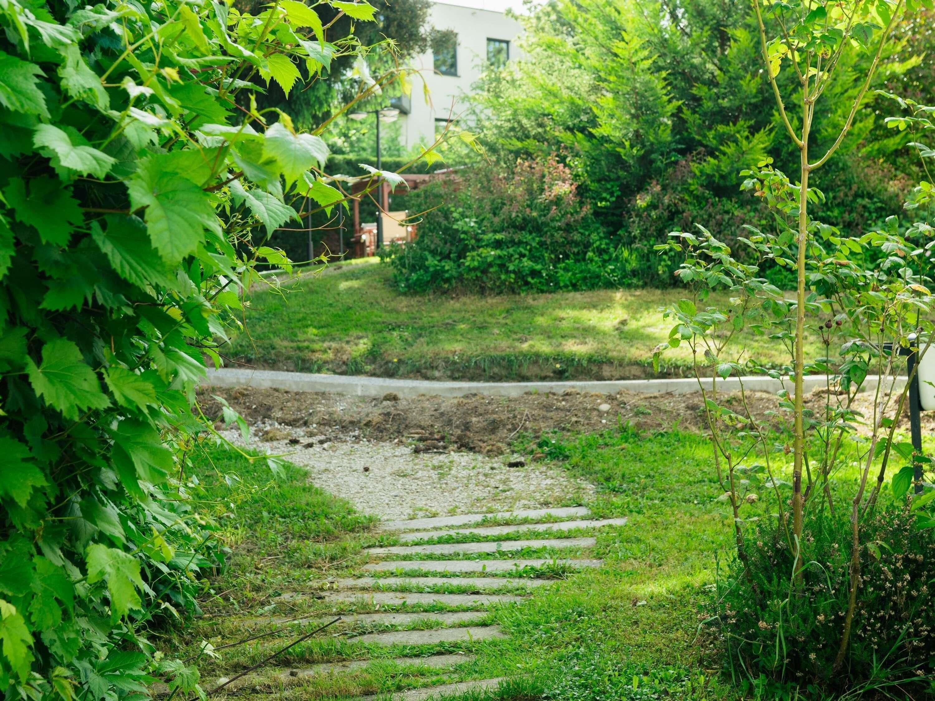 Um caminho de jardim que leva a um edifício com fachada branca.
