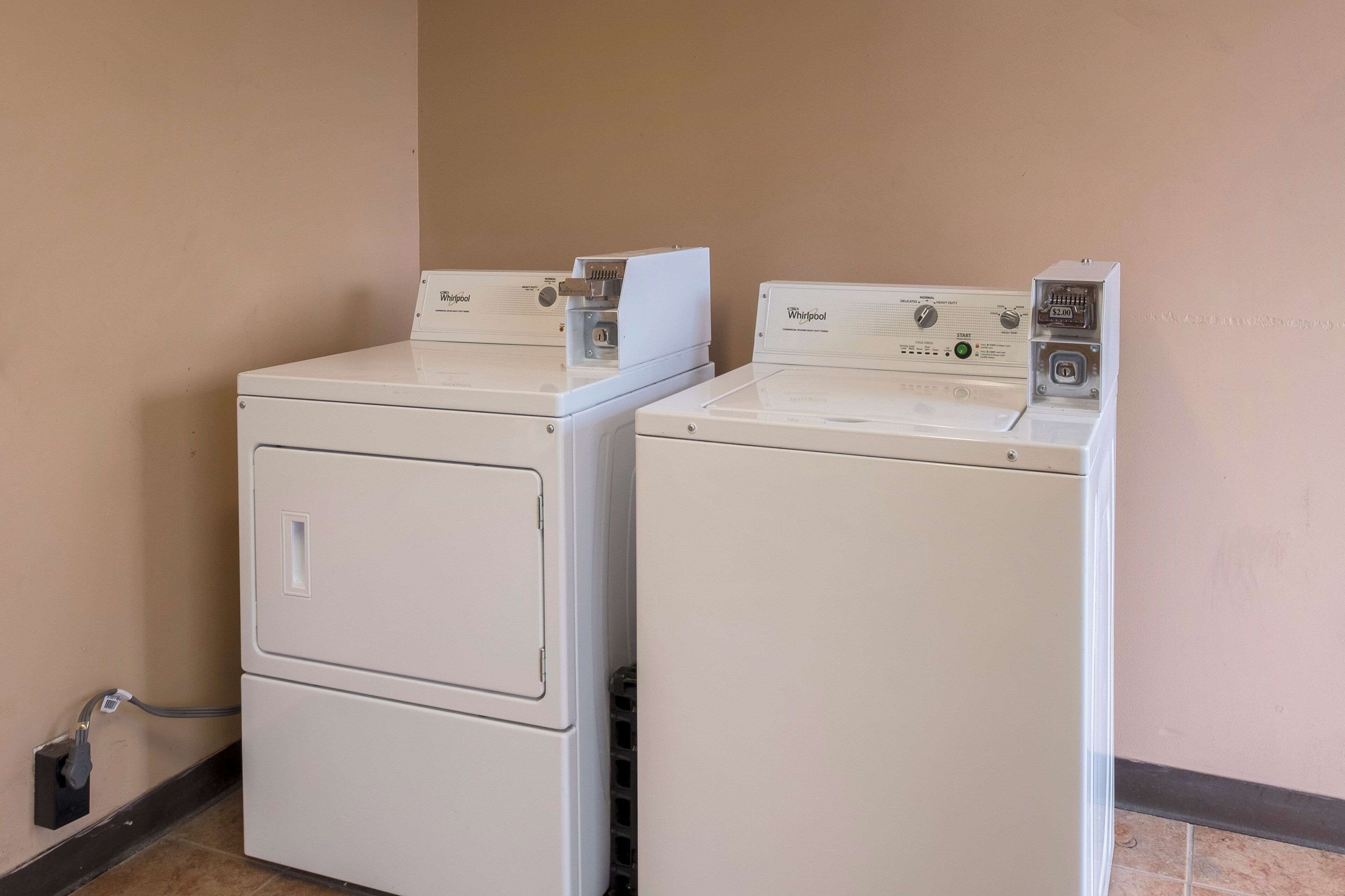 Duas máquinas de lavar roupa Whirlpool, uma sobre a outra, numa lavanderia.