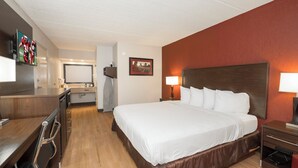 Quarto de hotel com cama, mesas de cabeceira, escrivaninha com cadeira, televisão e banheiro.
