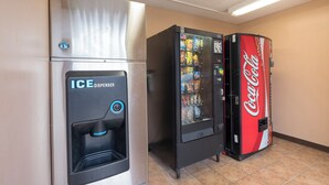 Área com máquina de vendas automática, dispensador de gelo e máquina de Coca-Cola.