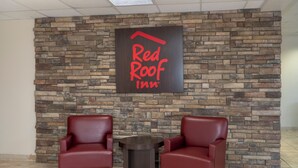 Placa do Red Roof Inn em uma parede de pedra, com duas poltronas de couro e uma pequena mesa na frente.