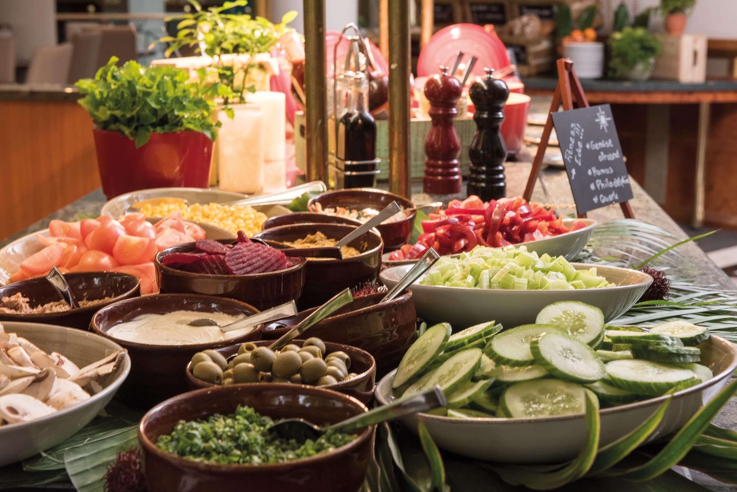 Mesa de buffet com diversos alimentos, incluindo frutas, legumes e patês.