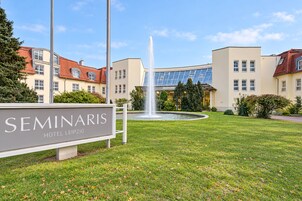 Um hotel chamado 'Seminaris Hotel Leipzig' com uma fonte, vegetação e edifícios modernos.