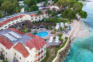 Vista aérea de um resort com piscina, praia e vários edifícios com telhados de telha vermelha.