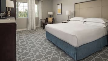 Quarto de hotel com cama grande, mesa, cadeira e janela com cortinas.