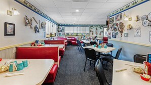 Um restaurante com cabines e mesas, decorado com tapeçarias e objetos de recordação.