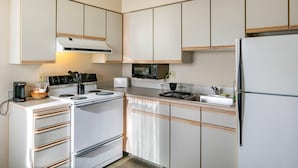 Uma cozinha moderna com armários brancos, fogão, micro-ondas e geladeira.