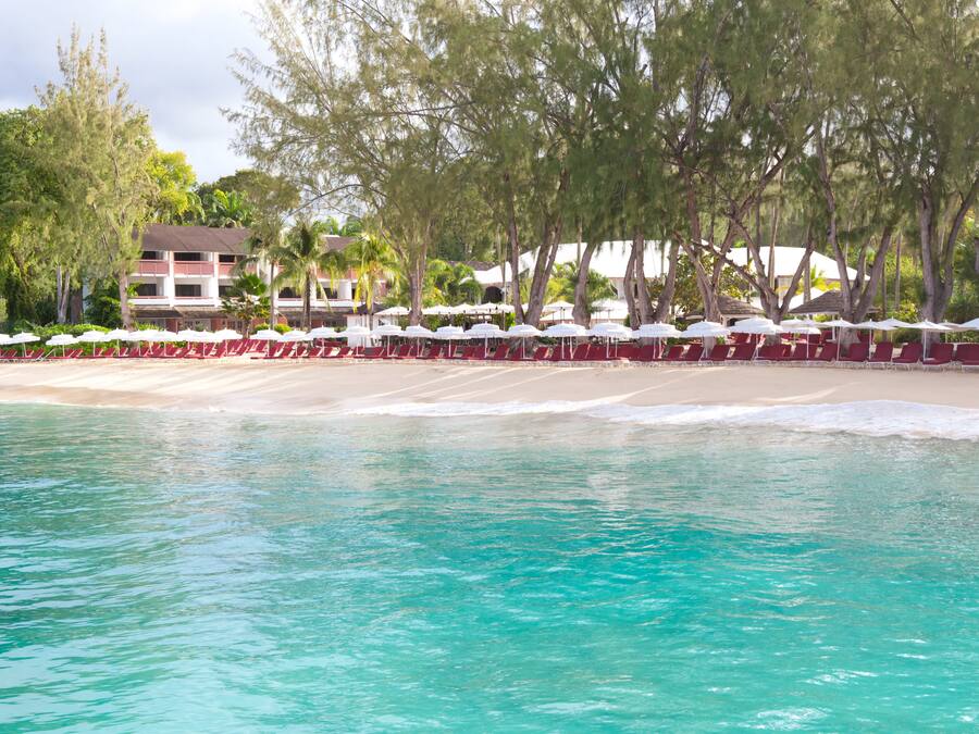 Na praia, areia branca, espreguiçadeiras, guarda-sóis