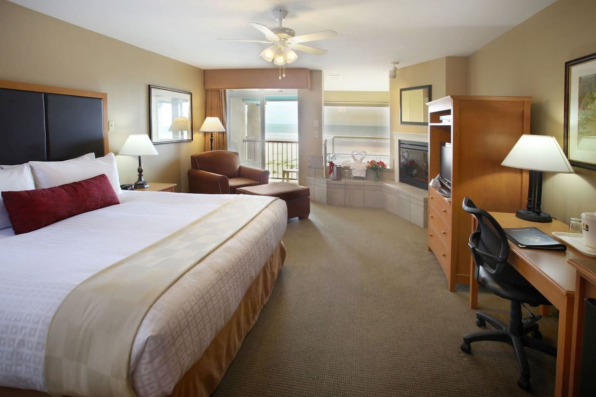 Quarto de hotel com cama, escrivaninha, cadeira e varanda com vista.