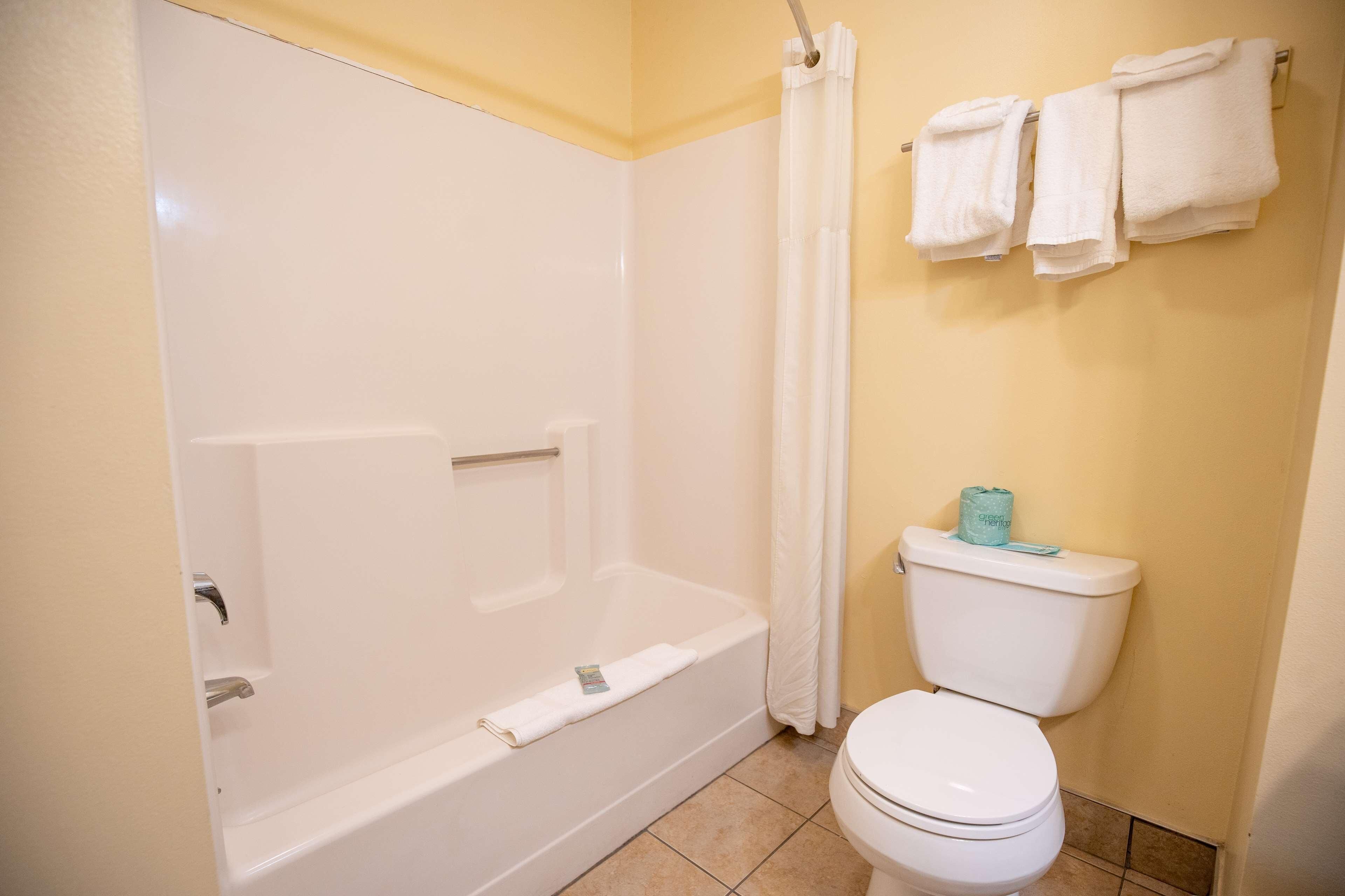 Casa de banho com banheira, sanita e um porta-toalhas com toalhas.
