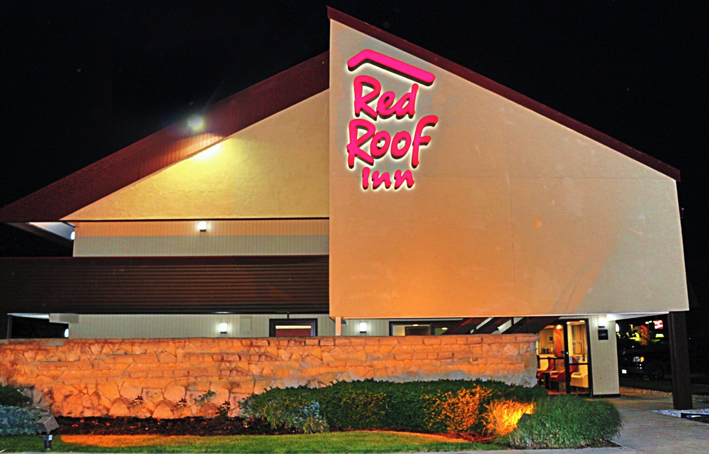 Edifício Red Roof Inn com fachada de pedra e um grande letreiro iluminado.
