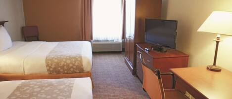 Quarto de hotel com duas camas, televisão, escrivaninha e cadeira.