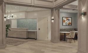 Um saguão de hotel com balcão de recepção, área de estar com mesa e cadeiras, e parede decorativa com arte abstrata.