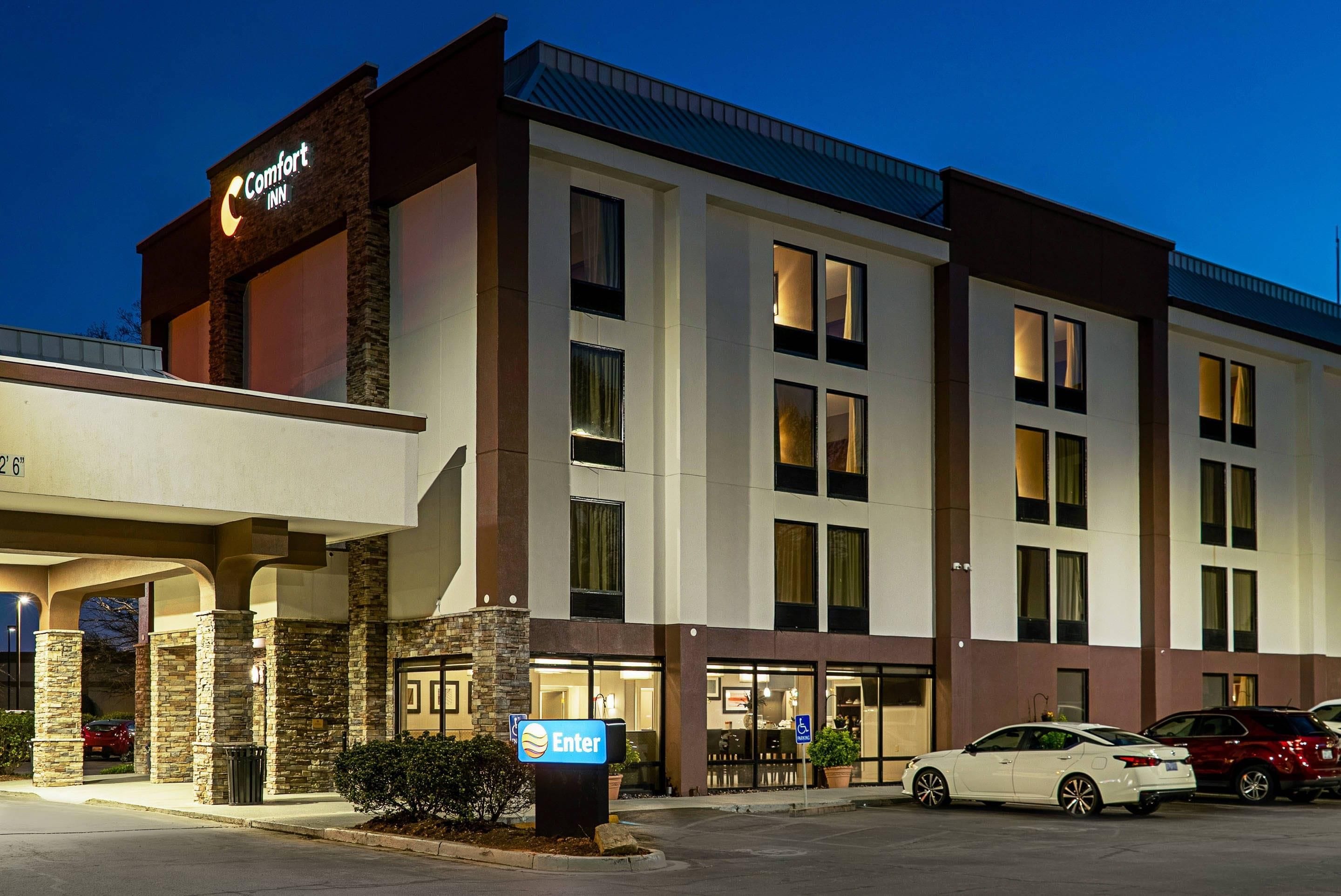 Um hotel Comfort Inn com design moderno, apresentando uma entrada imponente, área de estacionamento e uma placa com o nome do hotel.