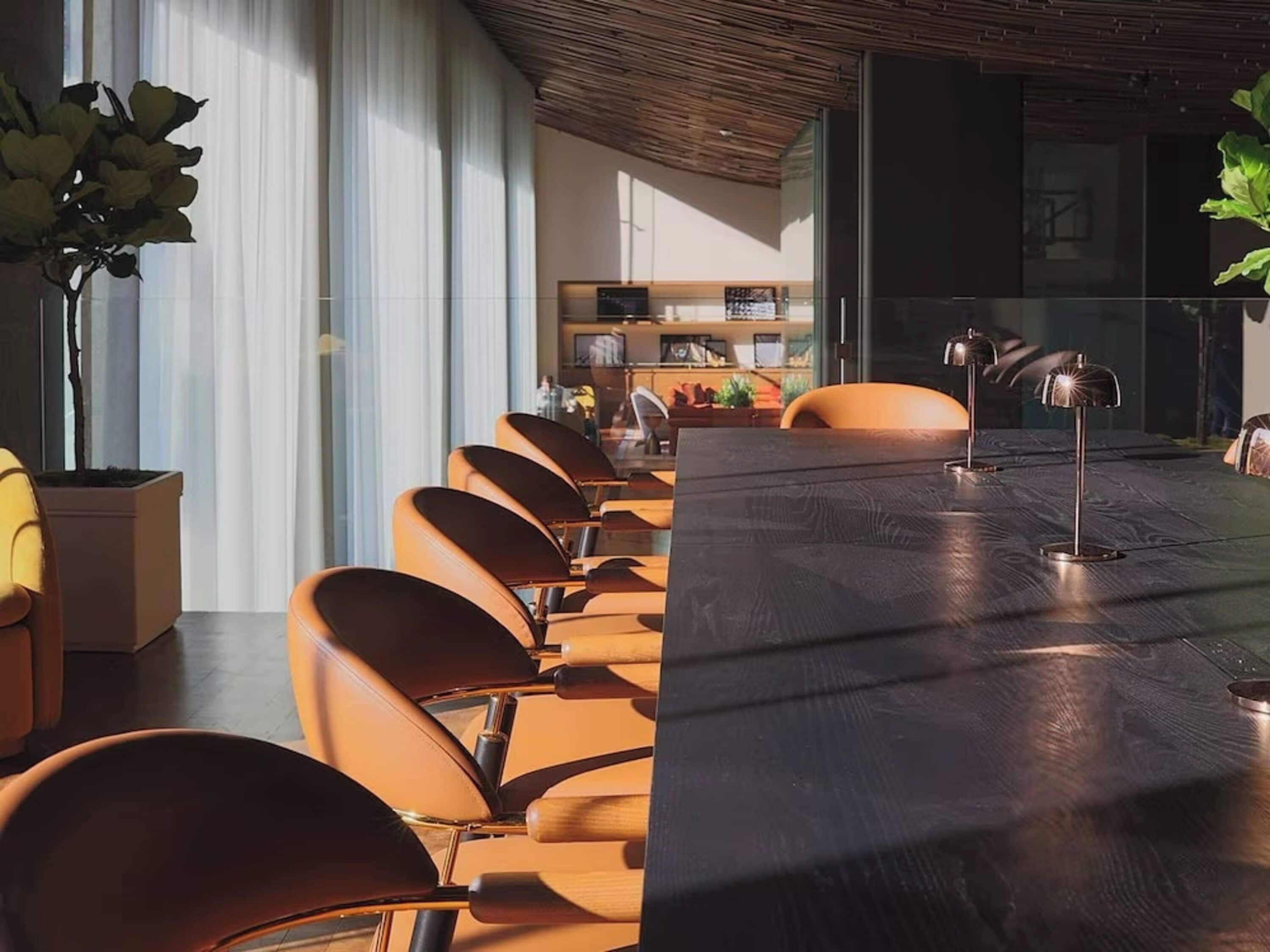 Uma sala de conferência com uma mesa comprida, cadeiras e teto moderno.