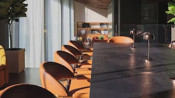 Uma sala de conferência com uma mesa comprida, cadeiras e teto moderno.