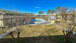 Um pátio com piscina, rodeado por edifícios com telhado verde e um céu azul claro.