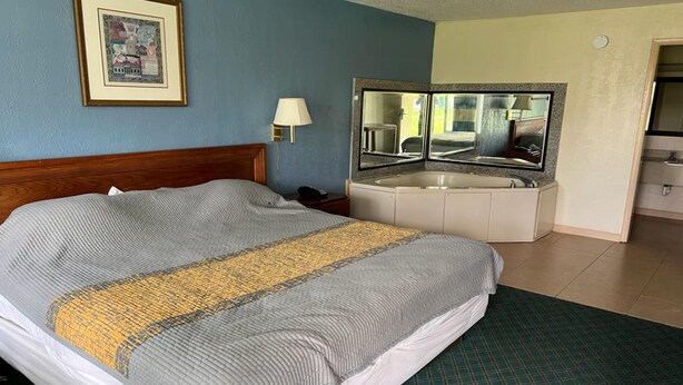 Quarto de hotel com cama, espelho, pia e quadro emoldurado na parede.