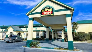 Edifício do Super Inn & Suites com uma placa visível, um estacionamento e um caminhão estacionado na frente.