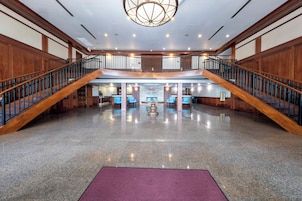 Um hall amplo com uma fonte central, duas escadas e um balcão de recepção.
