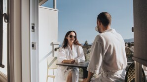 Um casal sentado à mesa ao ar livre, com vista para o céu e montanhas distantes.