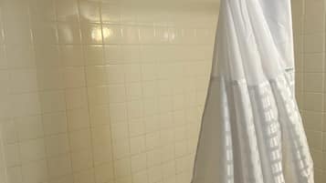 Casa de banho com paredes revestidas a azulejos brancos, uma banheira e um cortina de chuveiro.