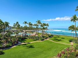 Um resort com piscina, palmeiras e vista para o oceano.