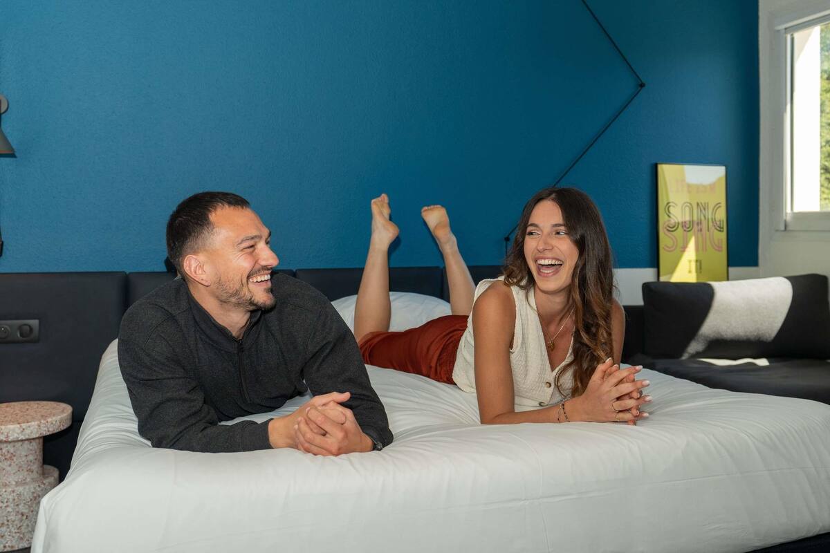 Quarto com cama, parede azul e um pôster.