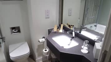 Uma casa de banho moderna com sanita, lavatório e espelho.