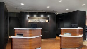 Uma área de recepção com dois balcões de madeira, um painel fixado na parede e uma televisão de tela plana.