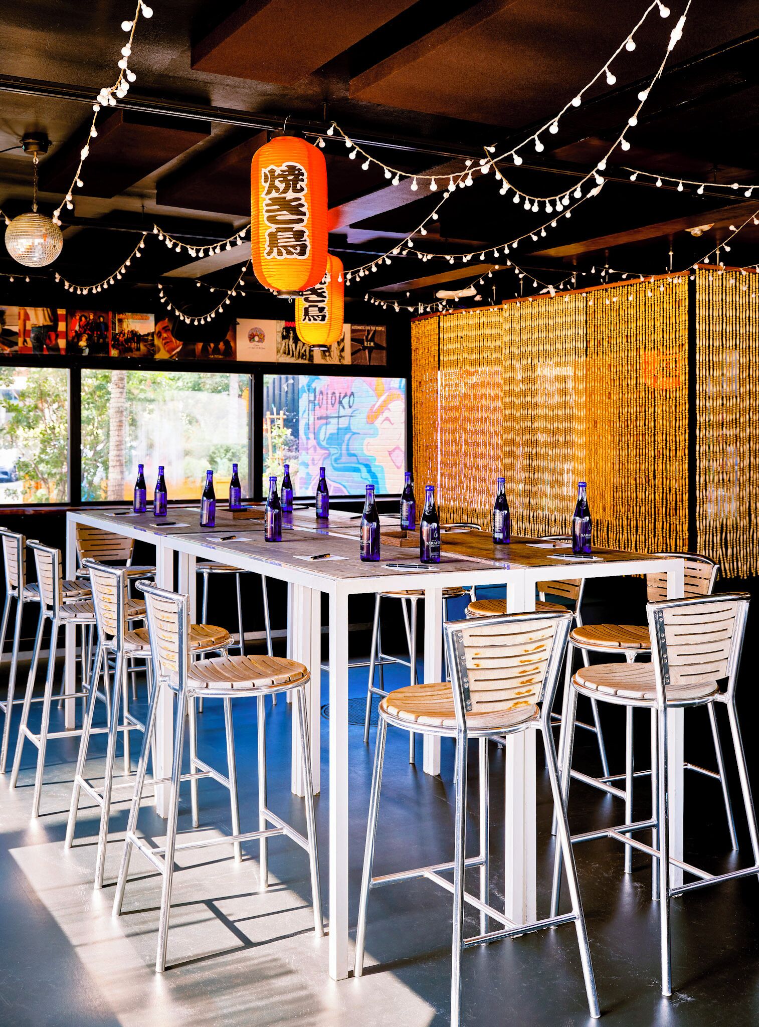 Uma área de bar com uma mesa comprida, várias cadeiras e garrafas.