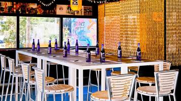 Uma área de bar com uma mesa comprida, várias cadeiras e garrafas.