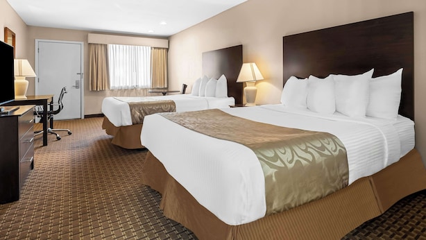 Quarto de hotel com duas camas, uma escrivaninha e uma cadeira.