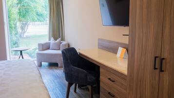 Quarto de hotel com cama, escrivaninha, poltrona, televisão e vista para o exterior.