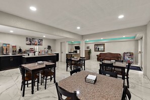 Um saguão de hotel moderno com área de refeições, bar e espaço para sentar.