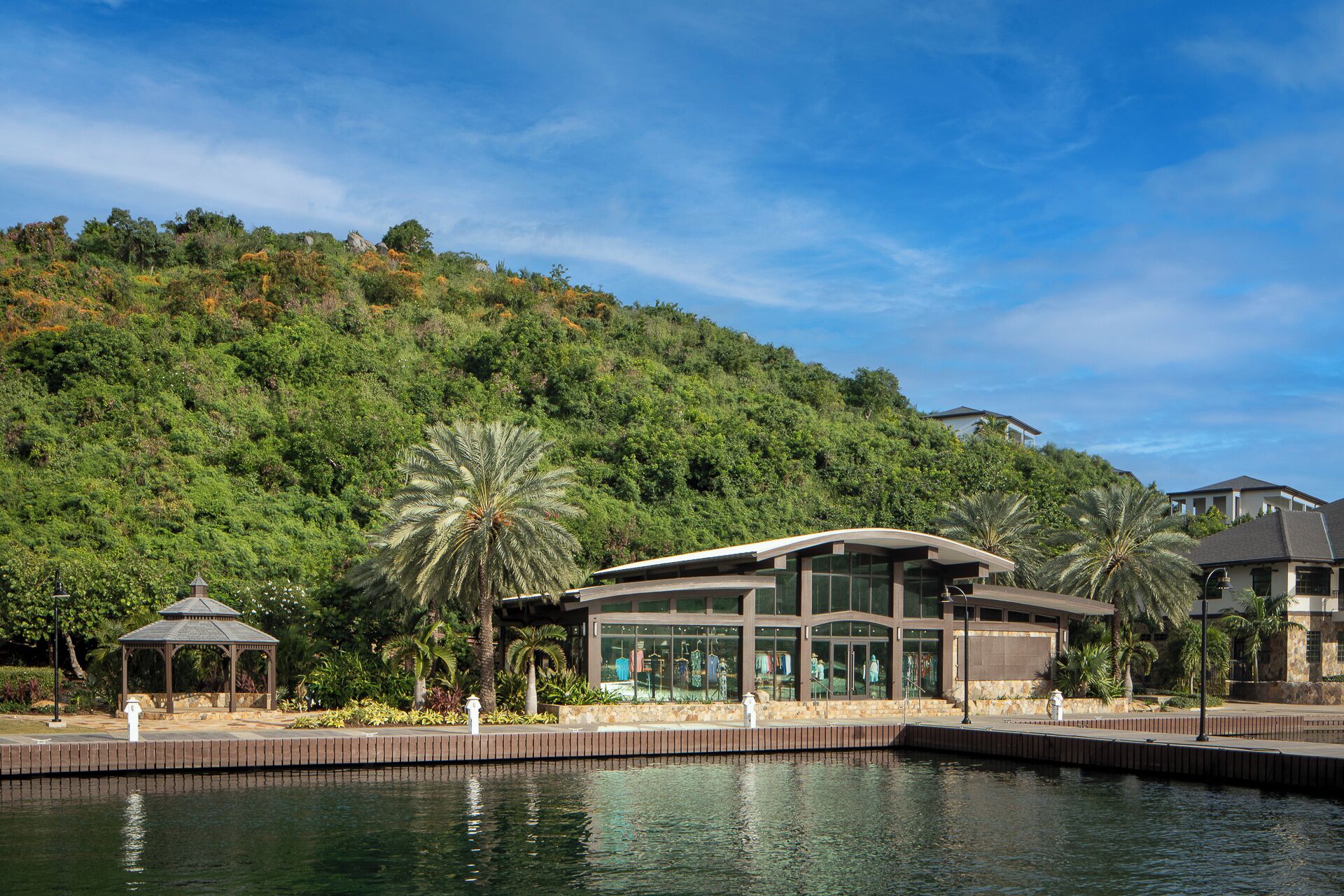 Um edifício moderno com janelas amplas, piscina e uma encosta verdejante ao fundo.