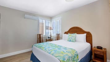 Quarto de hotel com uma cama grande, cabeceira de madeira, mesa de cabeceira e janela com persianas.
