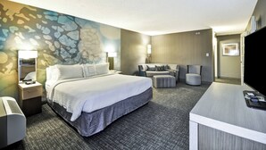 Quarto de hotel com cama grande, escrivaninha, cadeira e televisão.